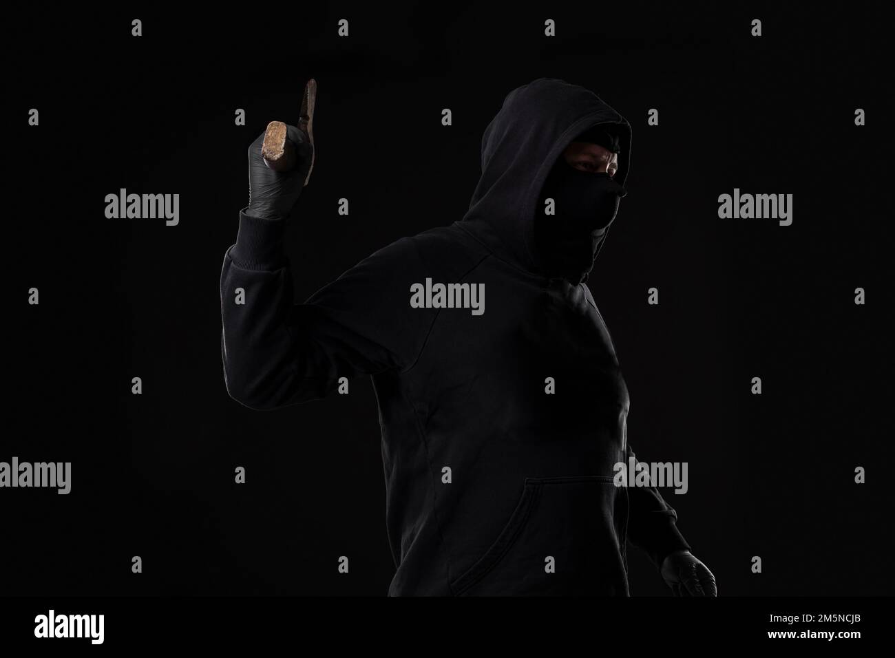 Bandit in black mask with hatchet on black background Stock Photo - Alamy