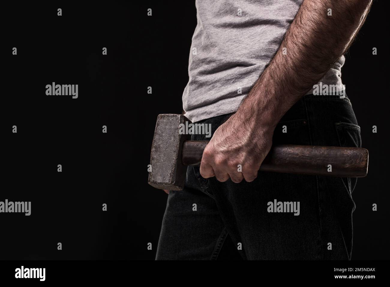 Male offender with a big hammer. On black background at the studio ...