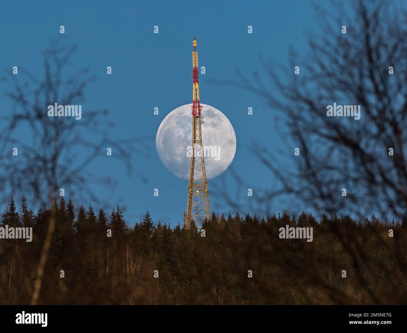 Full moon rises behind transmission mast Stock Photo - Alamy