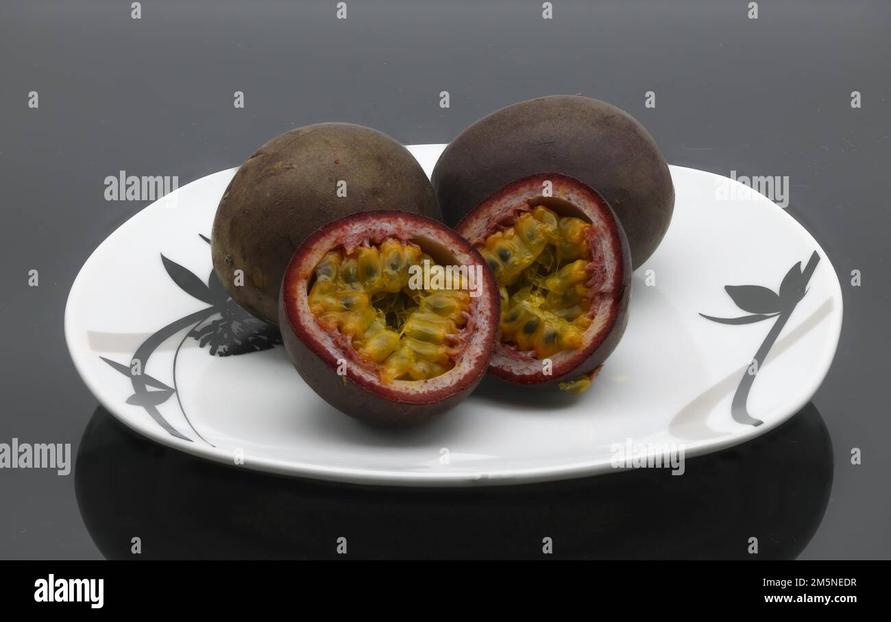 Passion fruit (Passiflora edulis) whole and sliced on plate Stock Photo ...