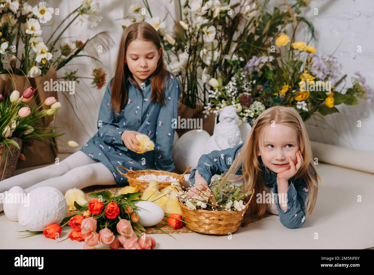 Two girls in a beautiful Easter photo zone with flowers, eggs, chickens ...