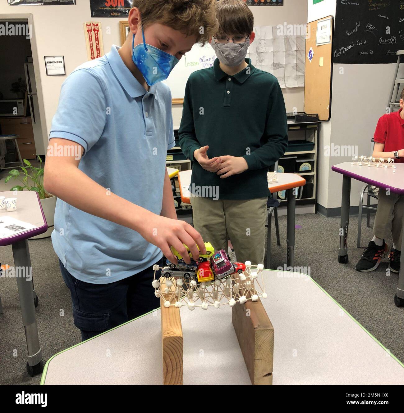 A student stacks toy cars on his bridge to test its strength during a ...