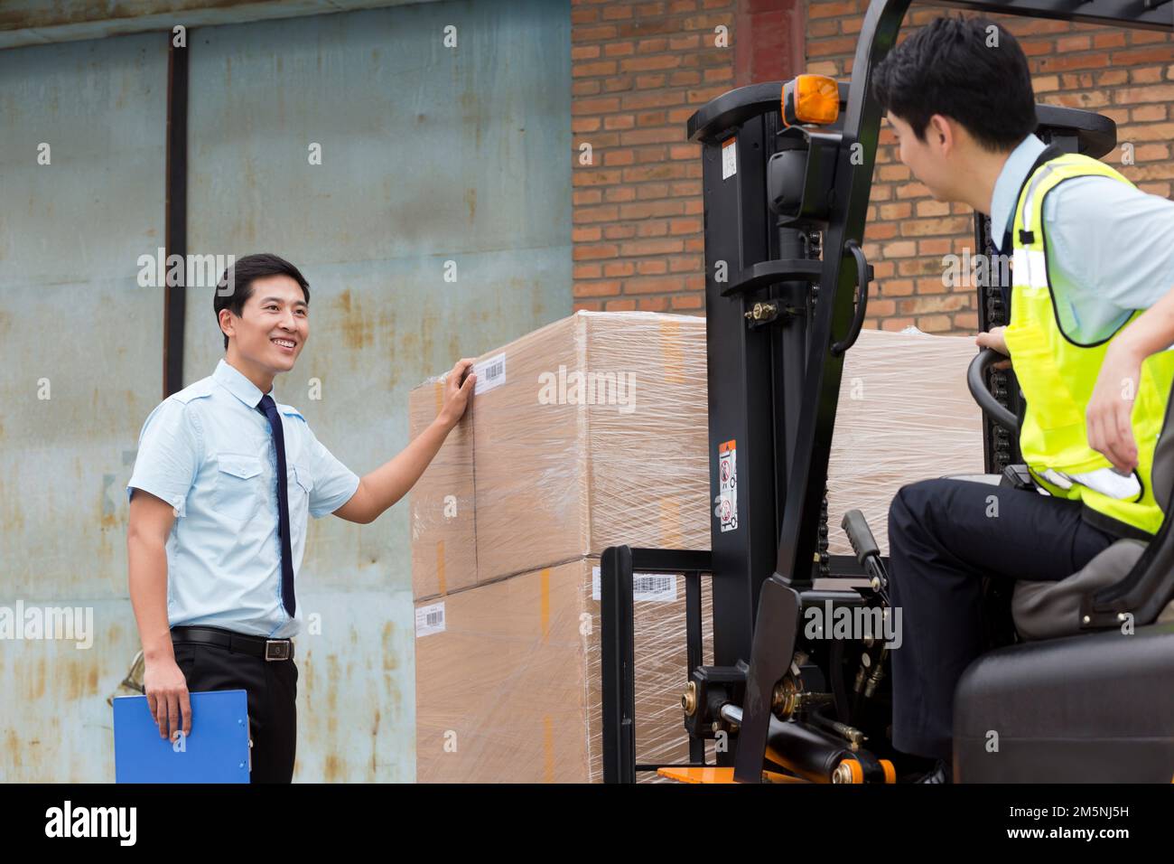 Logistics warehouse management personnel communicate with driving a ...