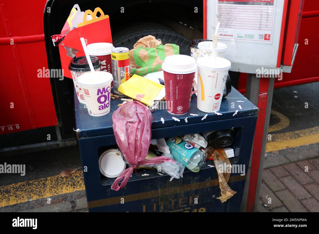 AN OVERFLOWING LITTER BIN WITH FOOD AND DRINK ITEMS INCLUDING COFFEE ...
