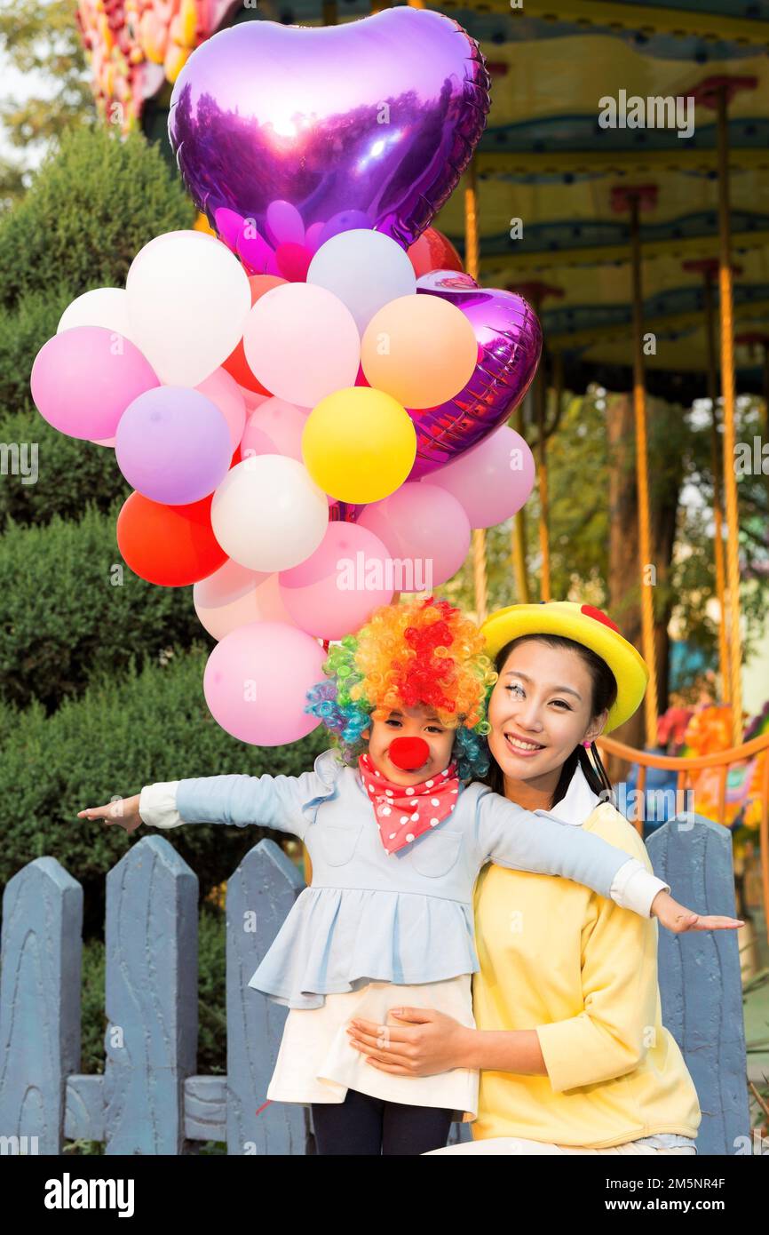 A young mother and daughter dressed as a clown in the amusement park to ...