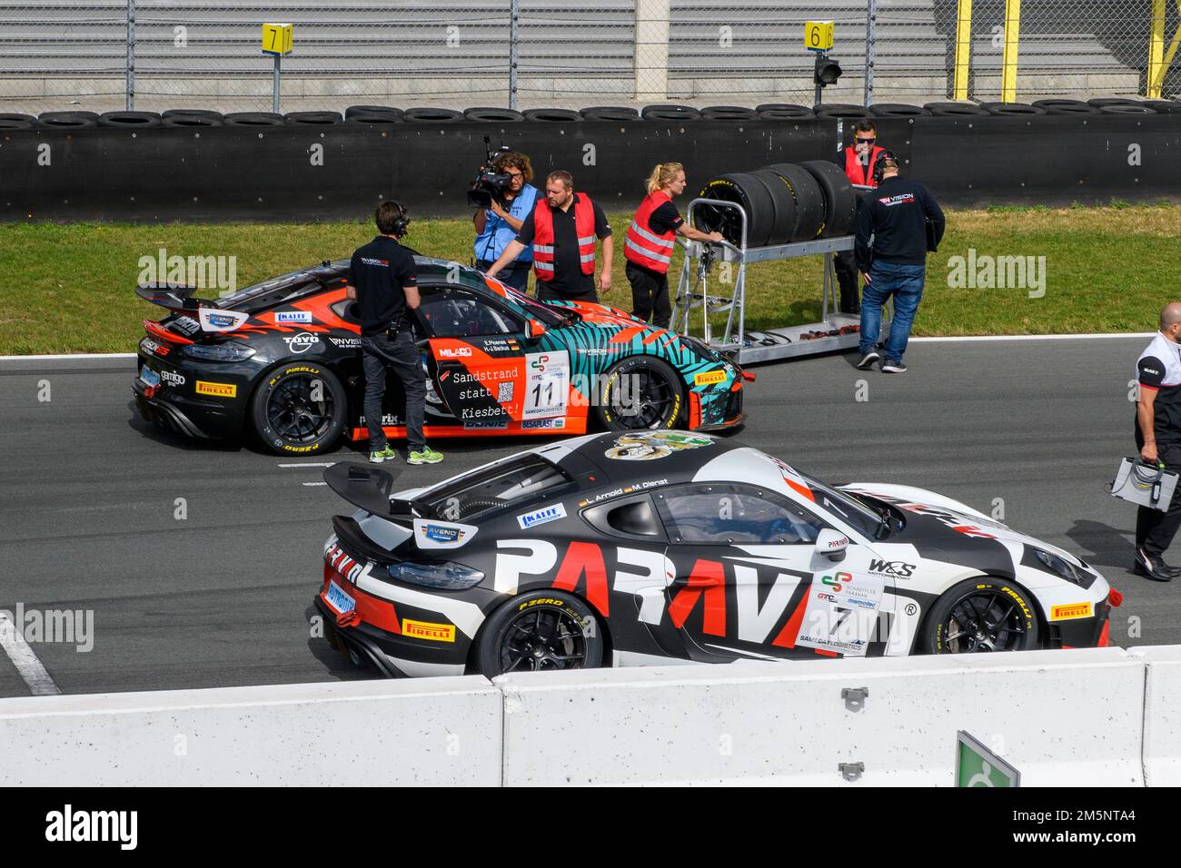 Team manager of car racing team and mechanic with spare tyres next to ...