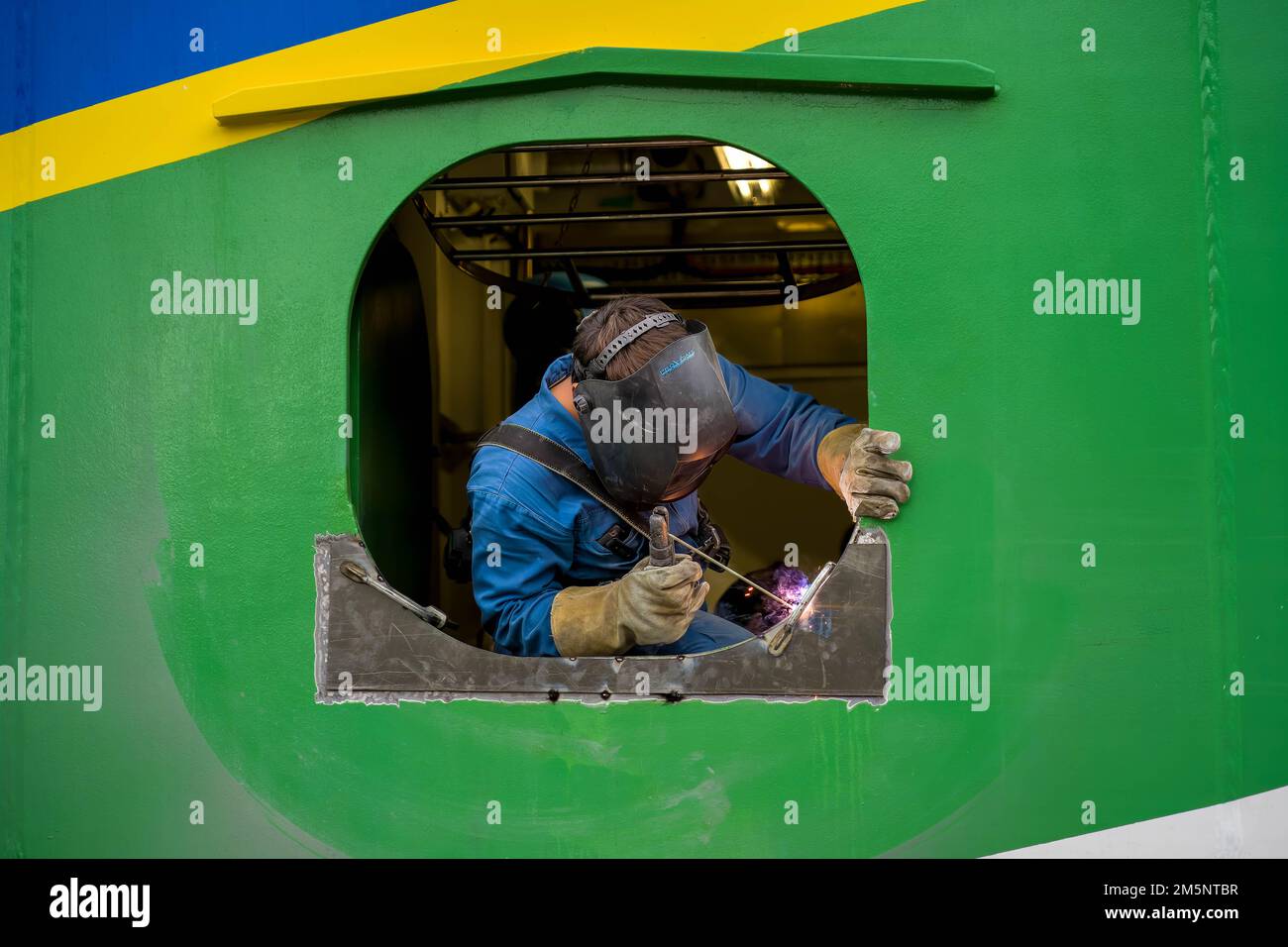 A welder making quick repairs on the hull of a large cruise ship while ...