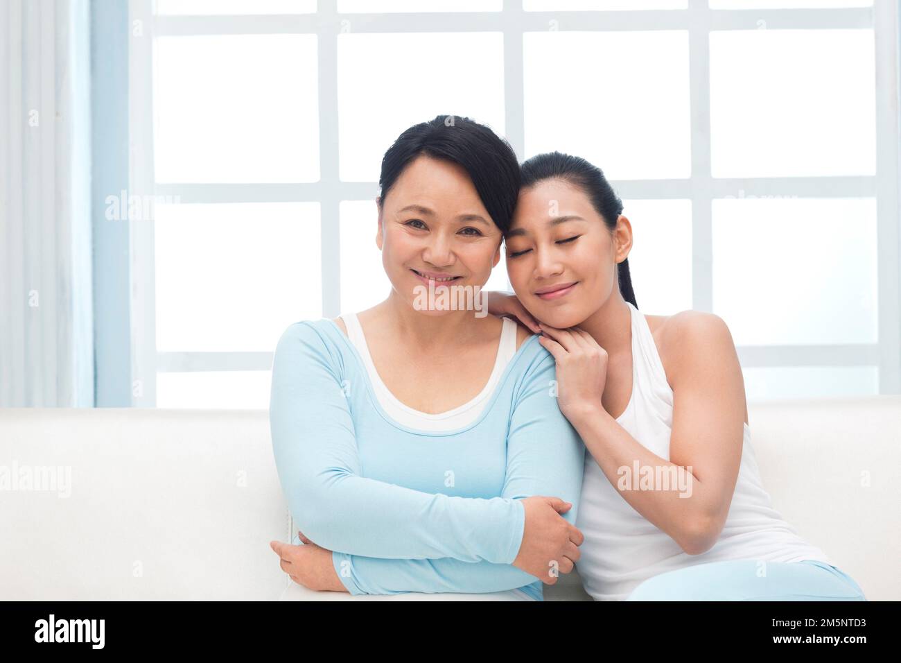 Intimate mother-daughter cuddling on the sofa Stock Photo - Alamy