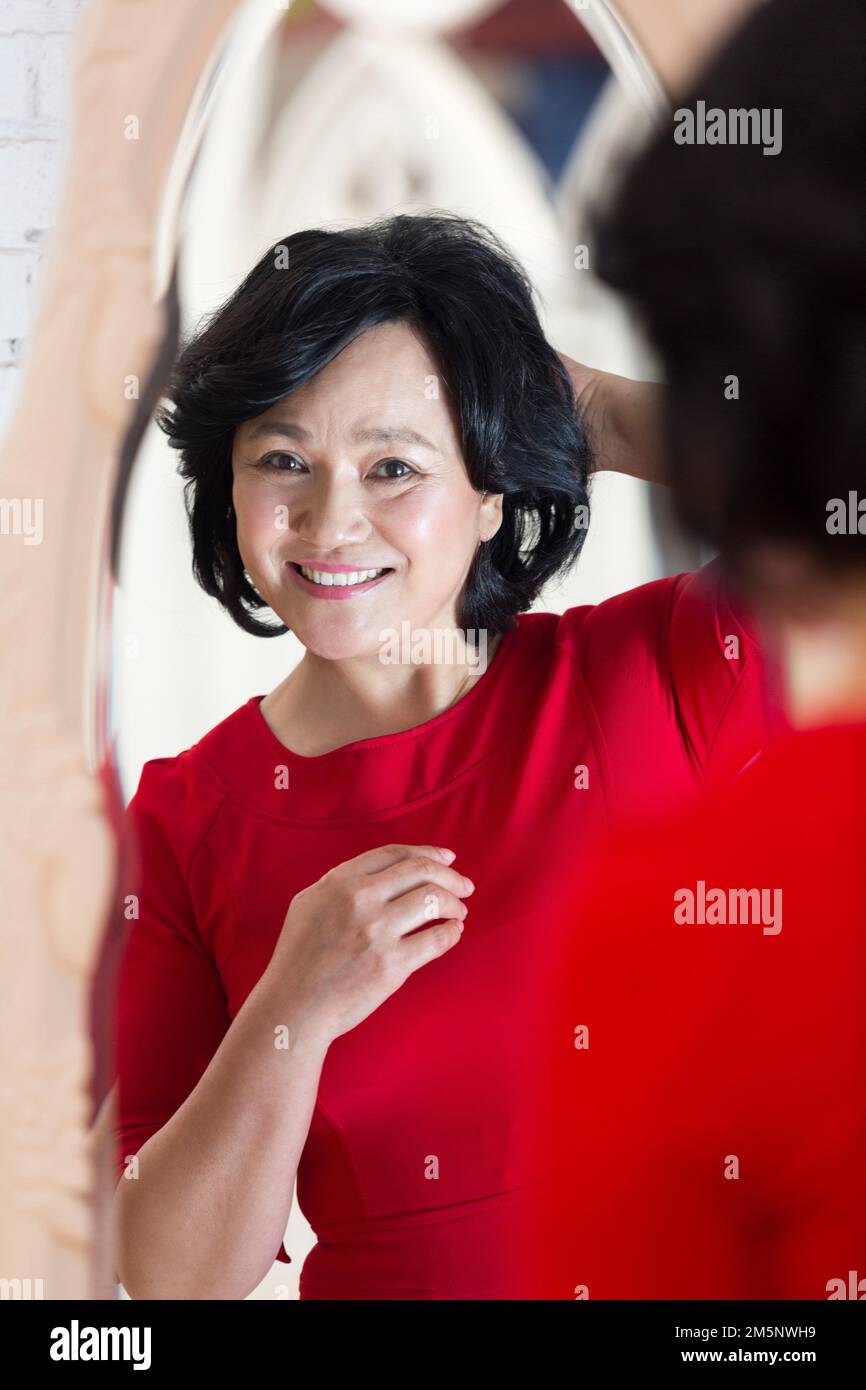 Elegant middle-aged woman look in the mirror Stock Photo - Alamy