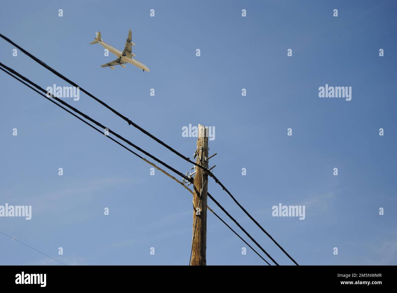 An aircraft plane flying over in the blue cloudy sky overa pole with ...