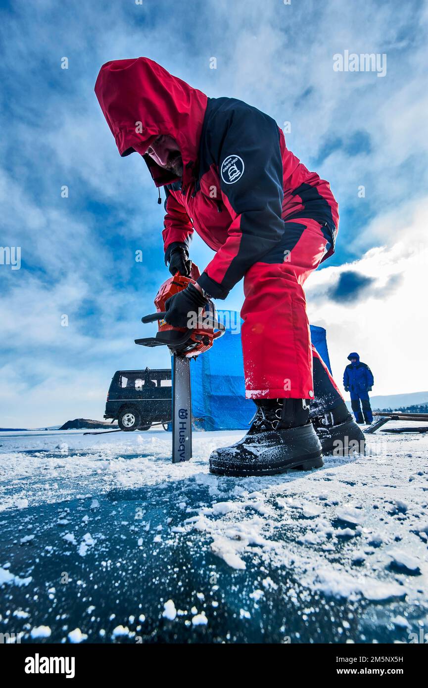 Digging a hole in ice for scuba divers with a chainsaw, Lake Baikal ...