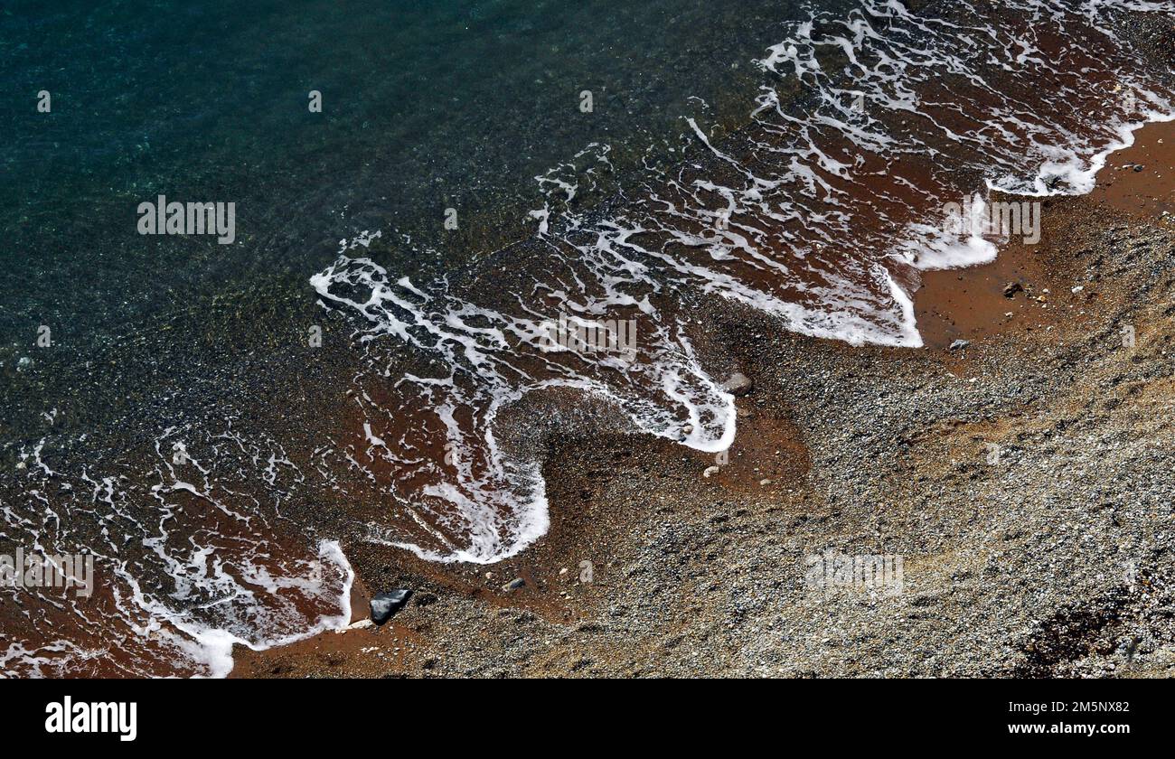 Gentle waves breaking on a sand and shingle beach on the coast close to ...