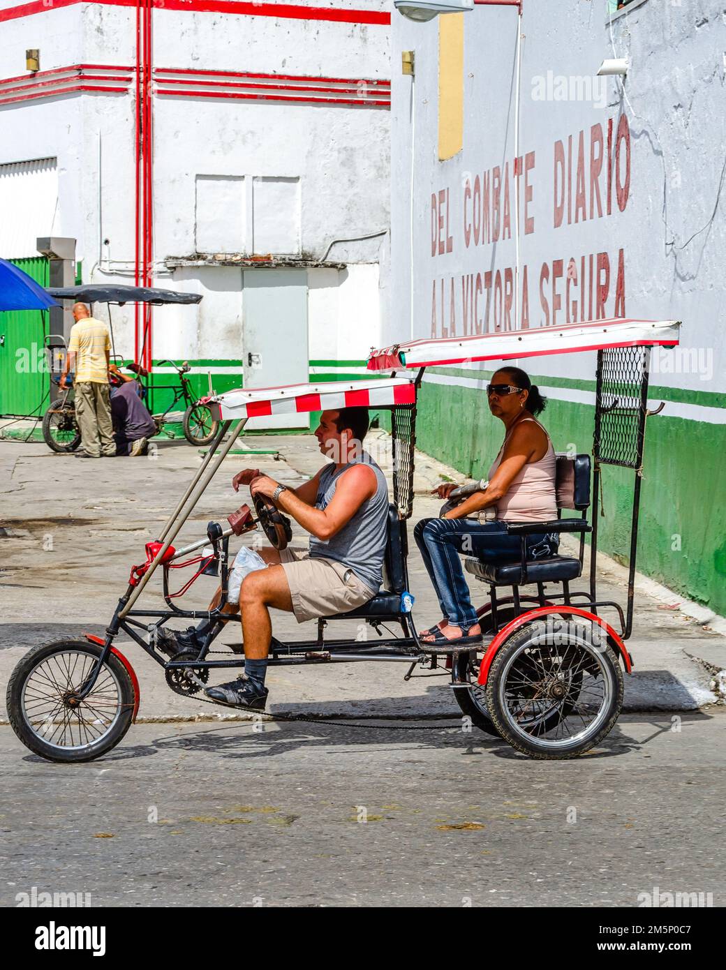 A man drives a pedicab or bicitaxi with a female passenger in the ...