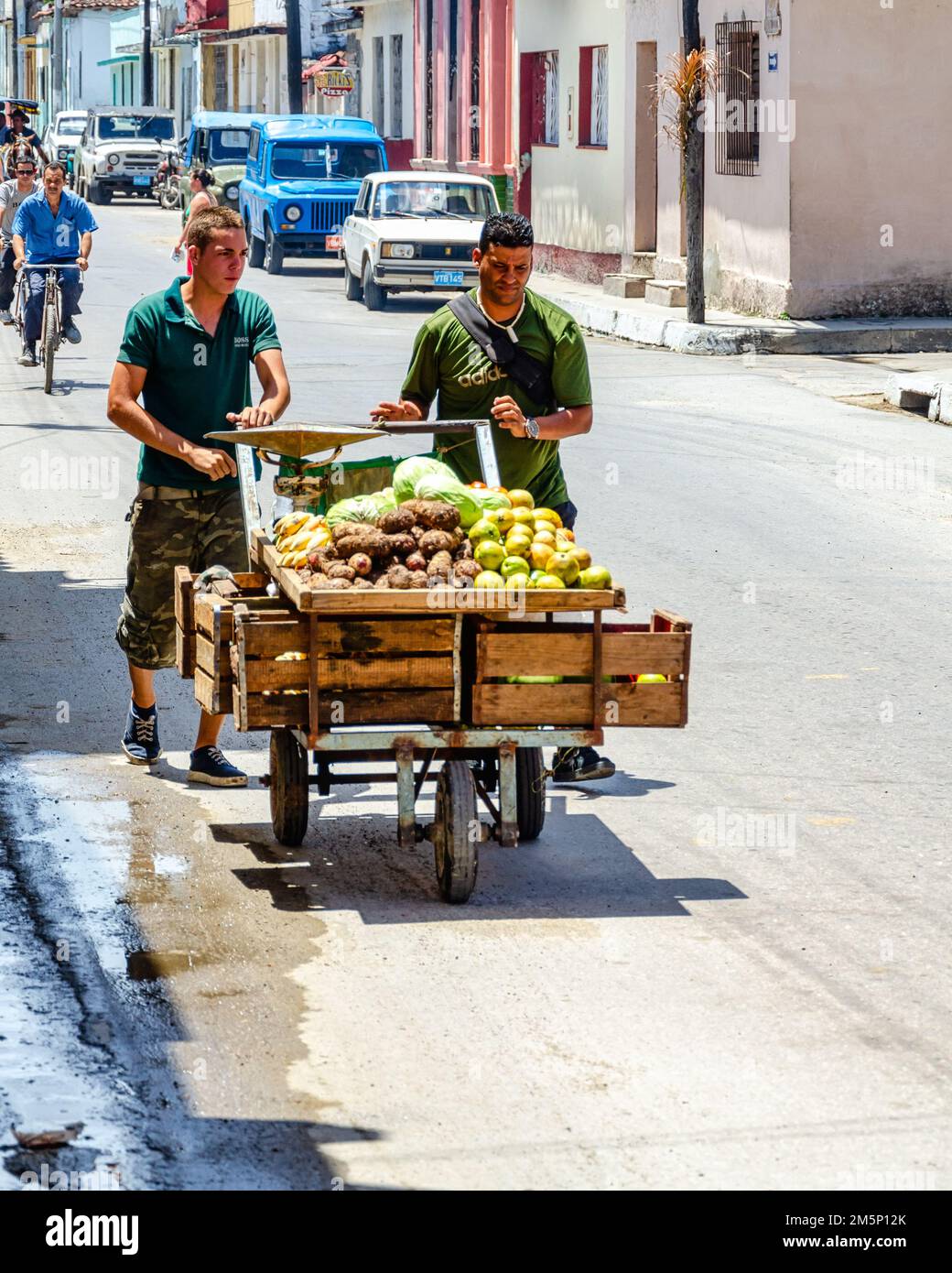 Two young Cuban men push a fruit and vegetable cars in the Colon St ...