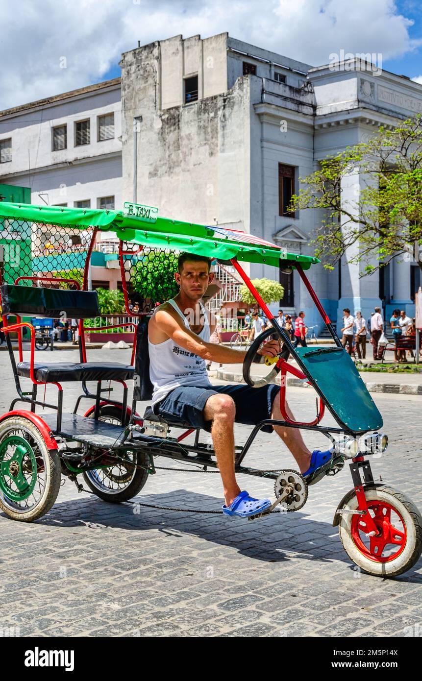 A young Cuban man works self-employed driving a bicitaxi or pedicab. He ...