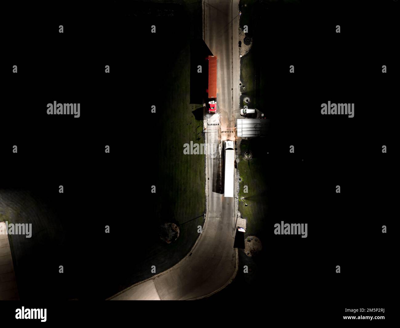 Aerial view of a sharp turn on a mountain road among green forest trees ...