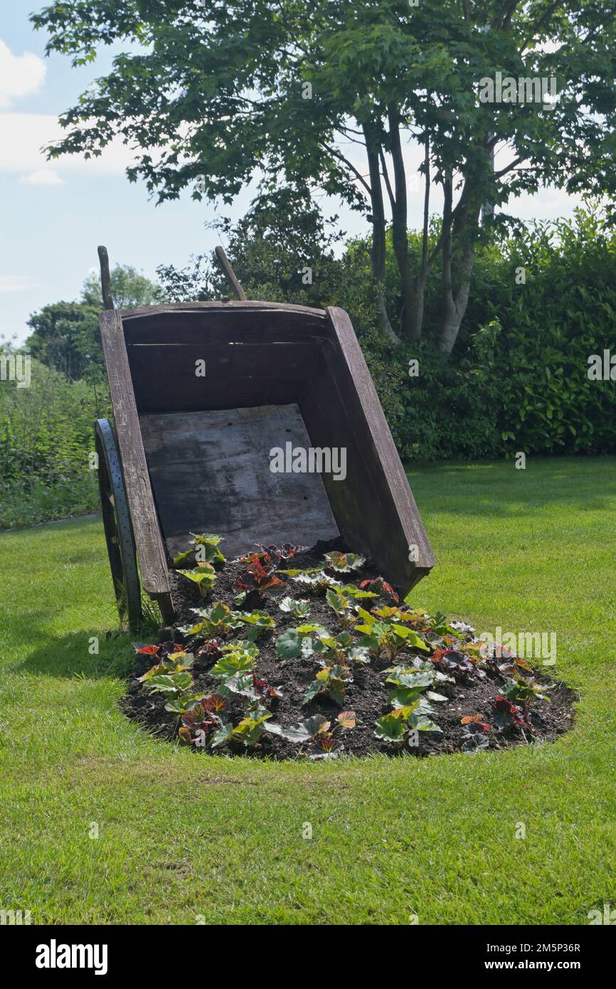 garden feature of tipped up cart and flowerbed Stock Photo - Alamy