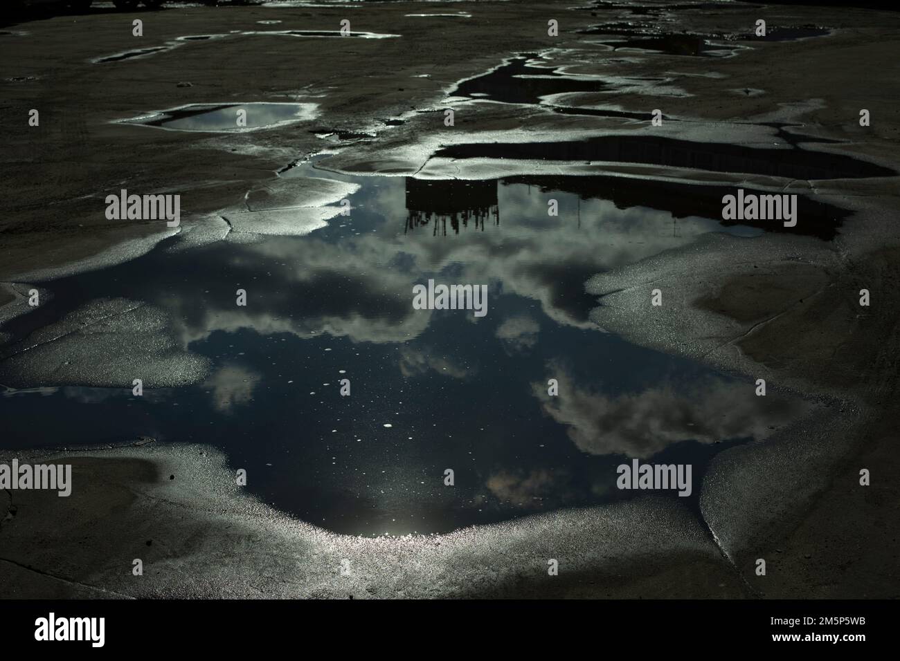 Puddle on pavement. After rain. Road in pits. Reflection of sky in ...