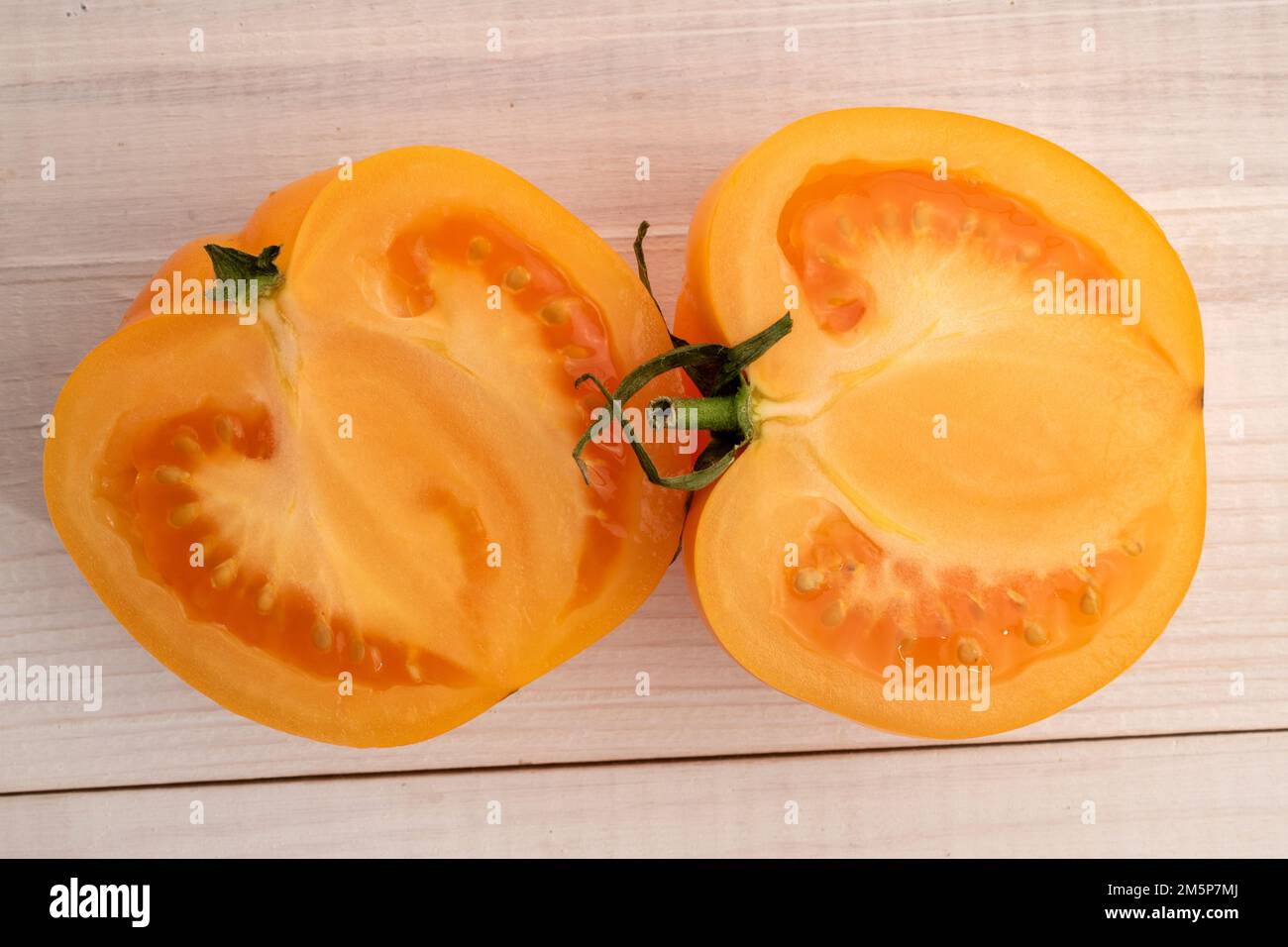 Two halves of fresh organic, juicy tomatoes, close-up, on a wooden ...
