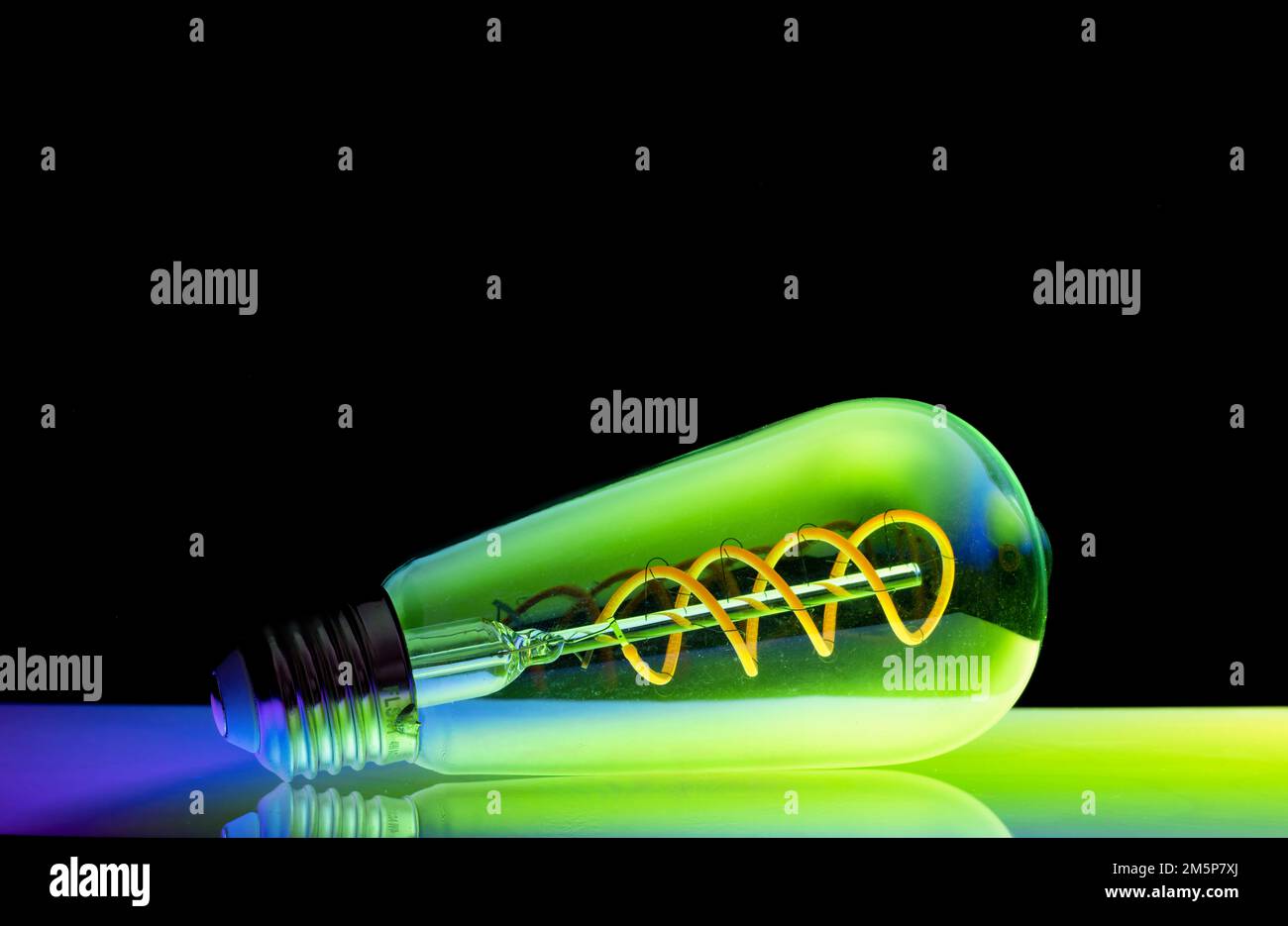 Colourful patterns reflect within a clear glass, oval shaped lightbulb ...