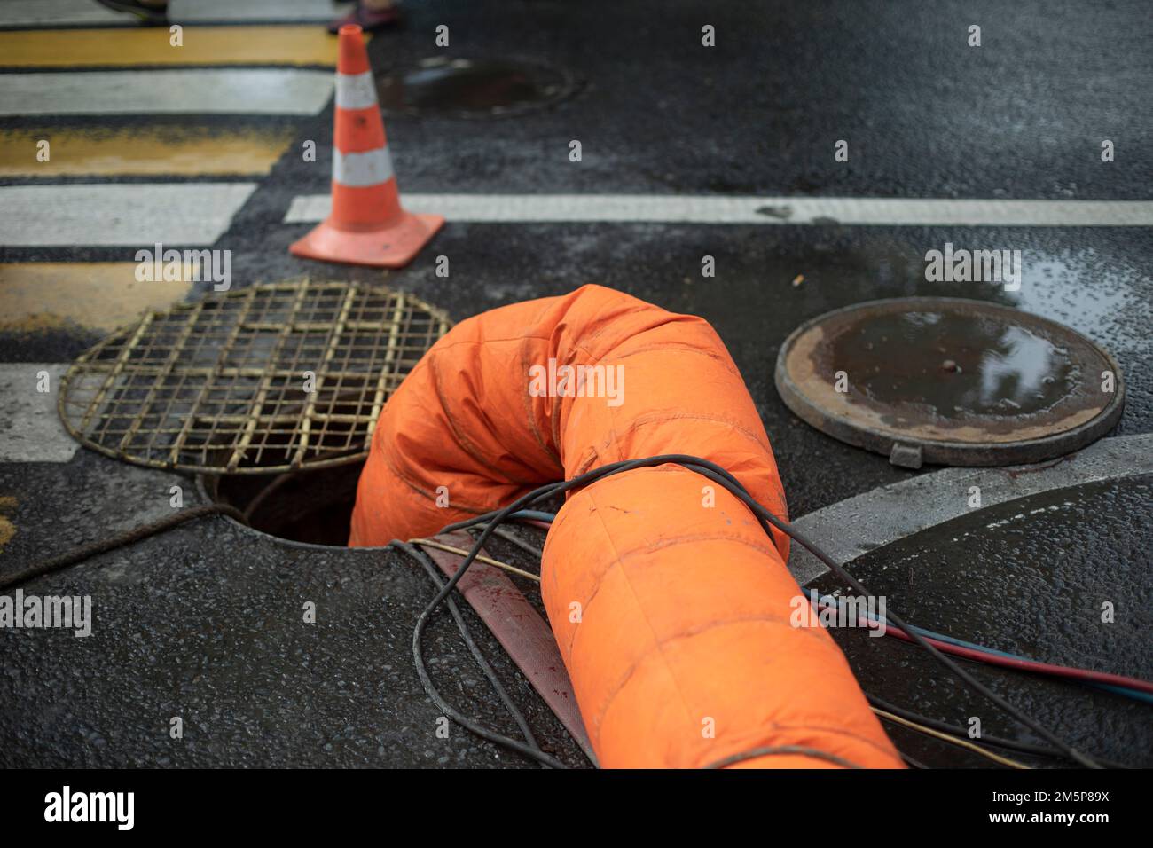 Orange pipe descends into hatch. Sewer repair. Wastewater pumping. Air ...