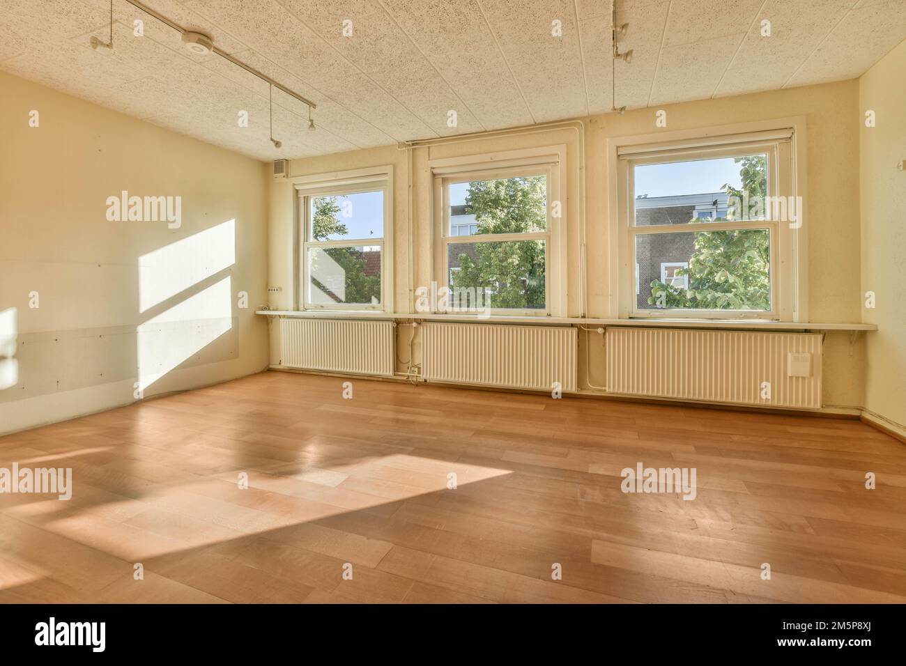 an empty room with wood flooring and two windows looking out onto the ...