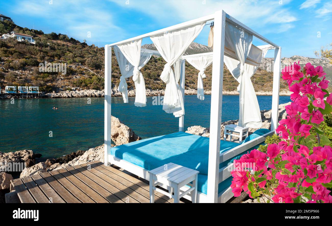 chaise lounge beds and curtains by the sea in a green bay, Antalya, Kas ...