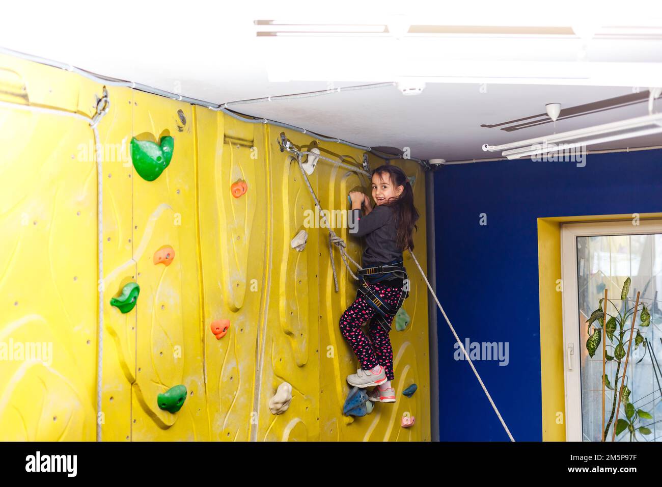 little girl climbing a rock wall indoor Stock Photo - Alamy