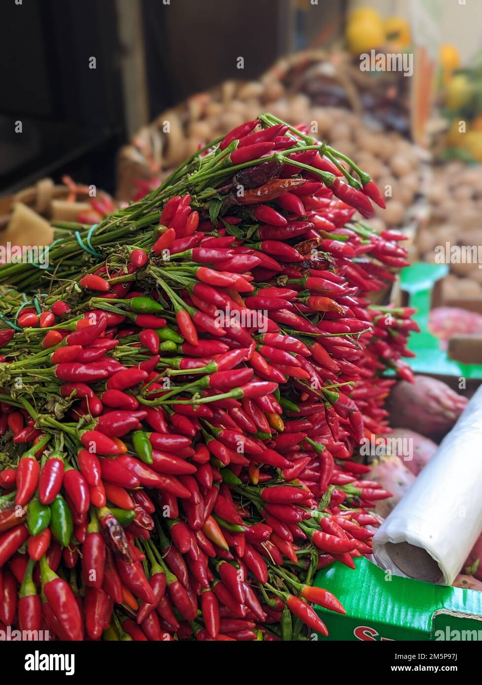 A vertical closeup of a bunch of red chilli peppers at a market Stock ...