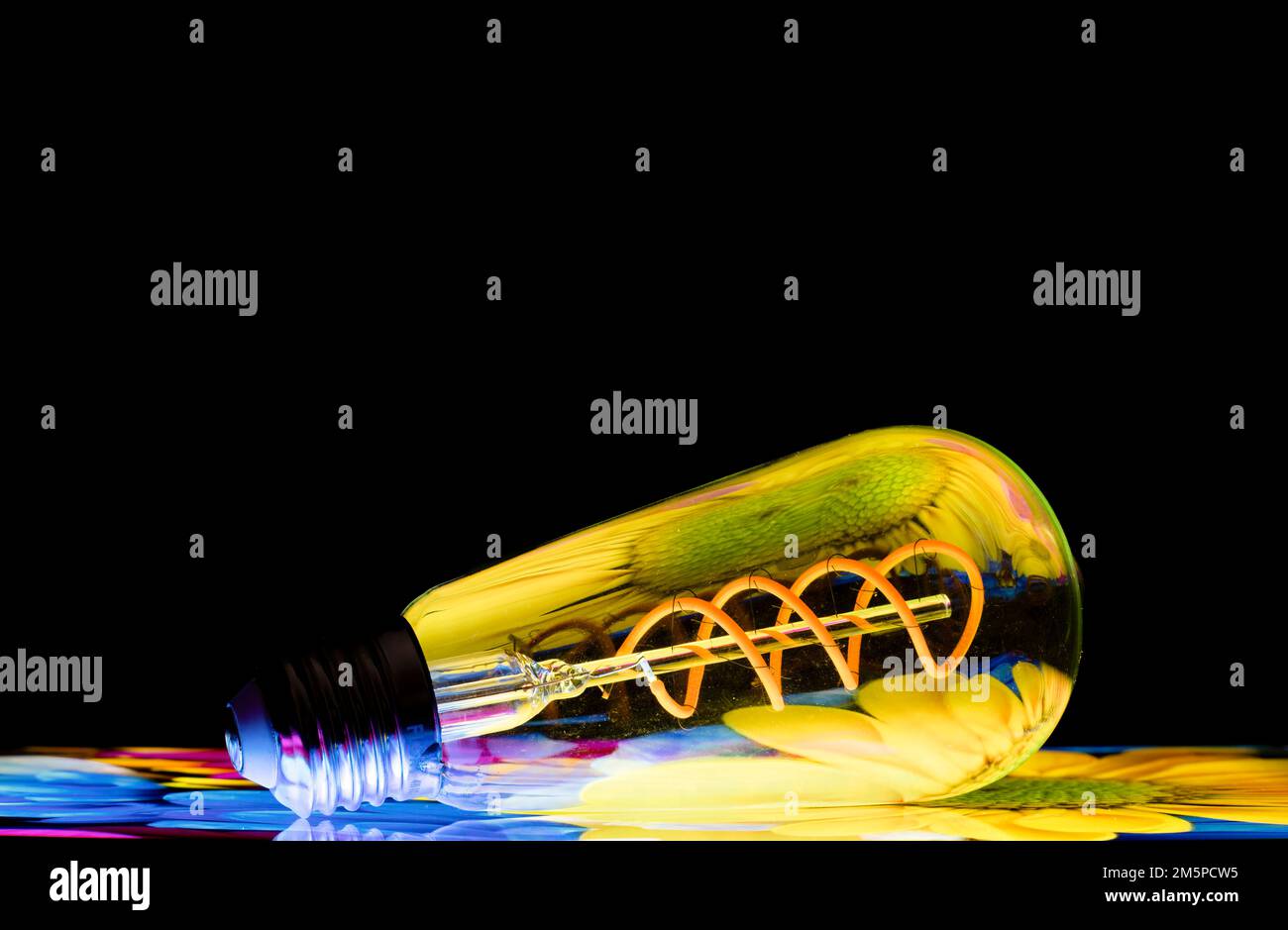 Colourful patterns reflect within a clear glass, oval shaped lightbulb ...