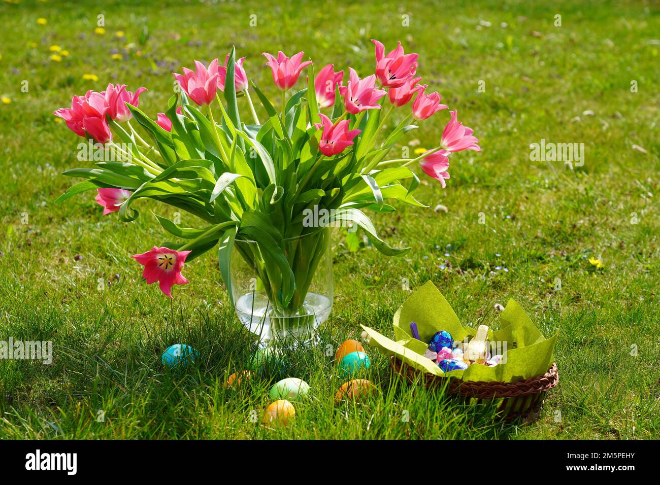 Beautiful pink roses in a vase, colorful Easter eggs, and a basket with ...