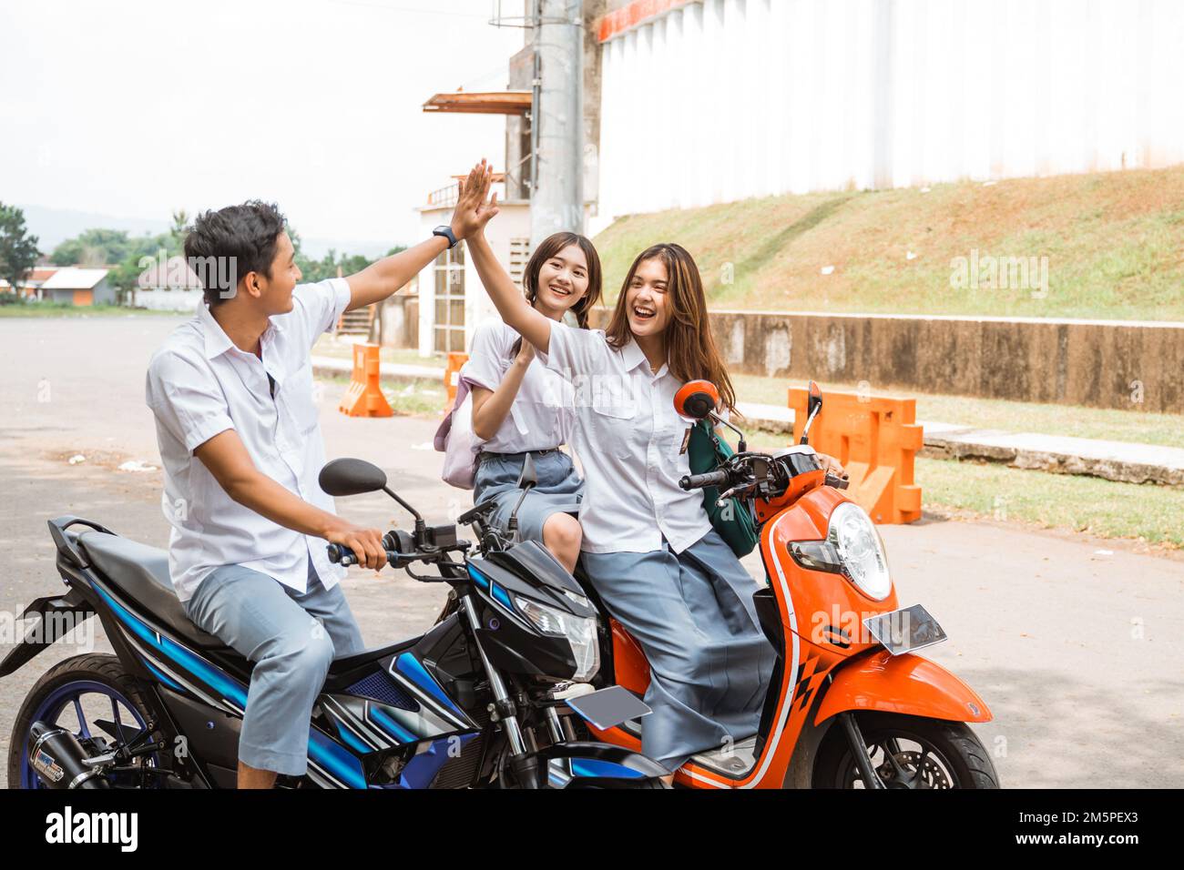 student girl riding motorcycle clapping hands with boy student Stock ...