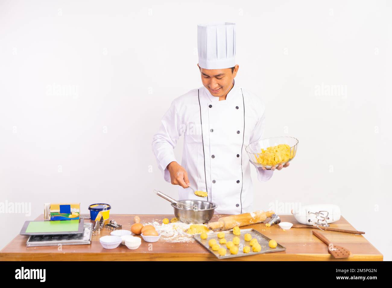 Asian male chef holding bowl and spoon behind kitchen counter Stock ...