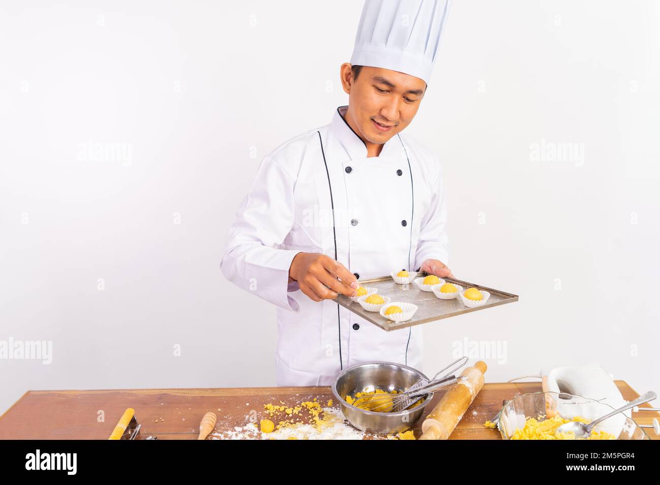 male chef holding and observing cake doneness on tray Stock Photo - Alamy