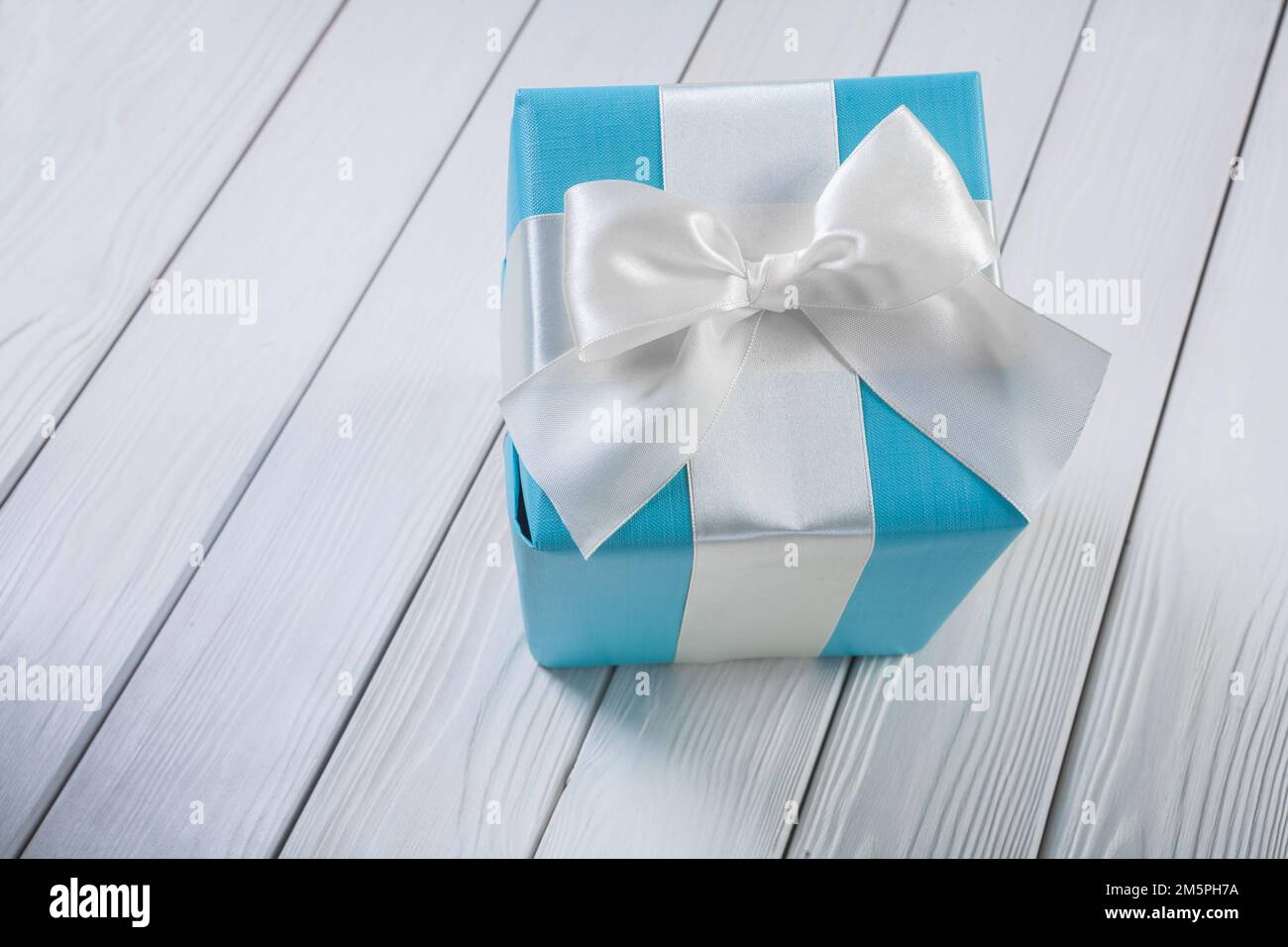 blue gift box with white bow on white wooden boards Stock Photo - Alamy