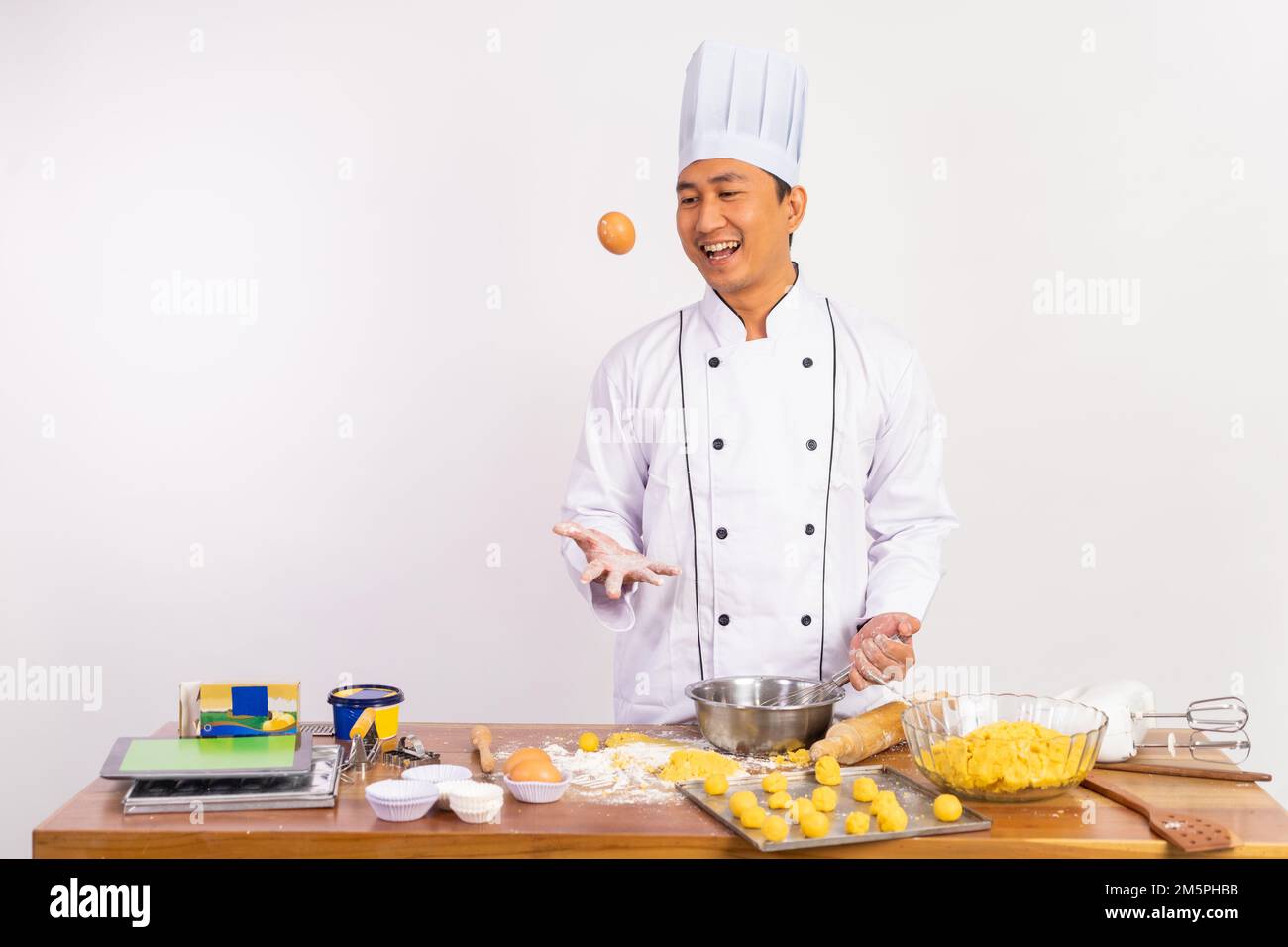 male chef throwing eggs while making dough Stock Photo - Alamy