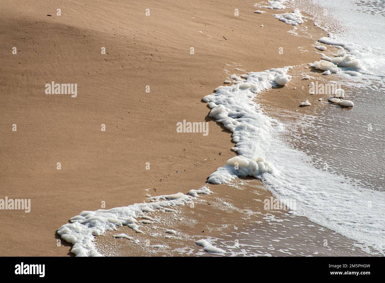 Gentle ocean waves wash onto the sandy shoreline of Praia da Cresmina near Guincho, Portugal ...