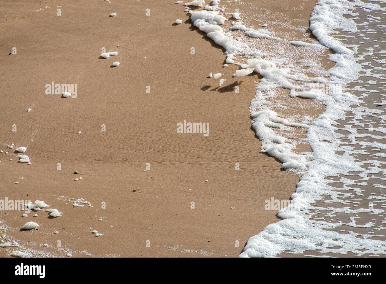 Gentle ocean waves wash onto the sandy shoreline of Praia da Cresmina near Guincho, Portugal ...