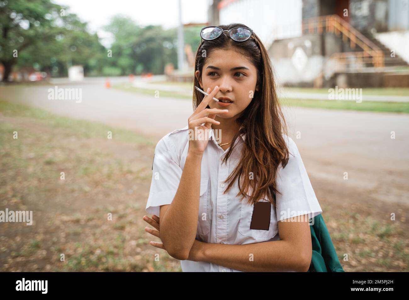 A girl student wearing a high school uniform smoking Stock Photo - Alamy