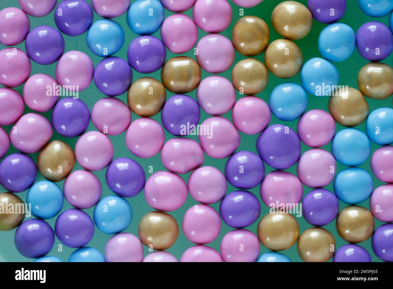 A top view shot of small colorful circle-shaped candies on a green ...