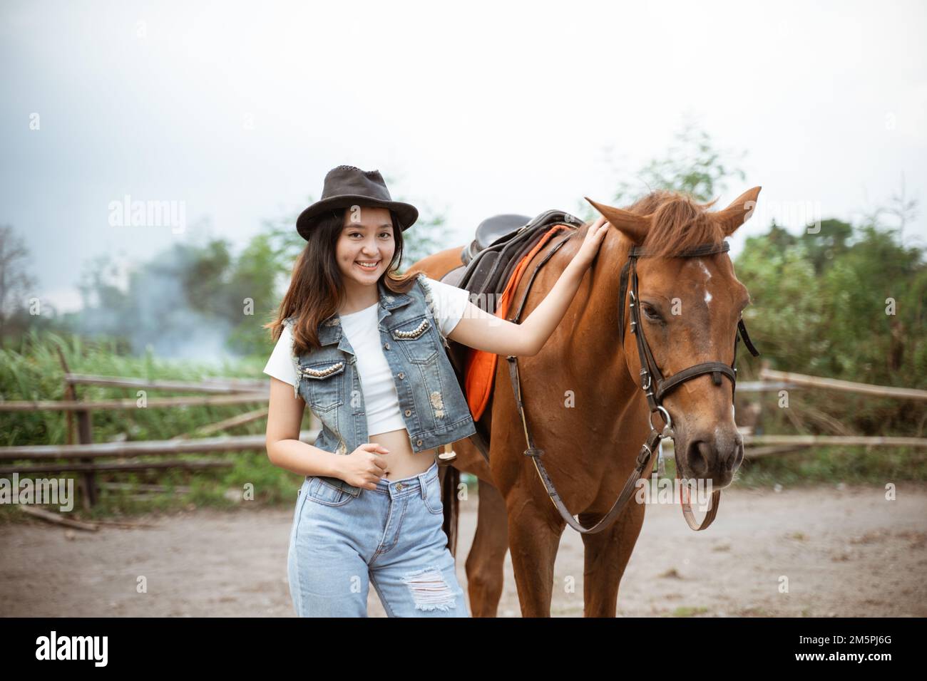 beautiful asian cowboy girl standing beside horse on outdoor background ...
