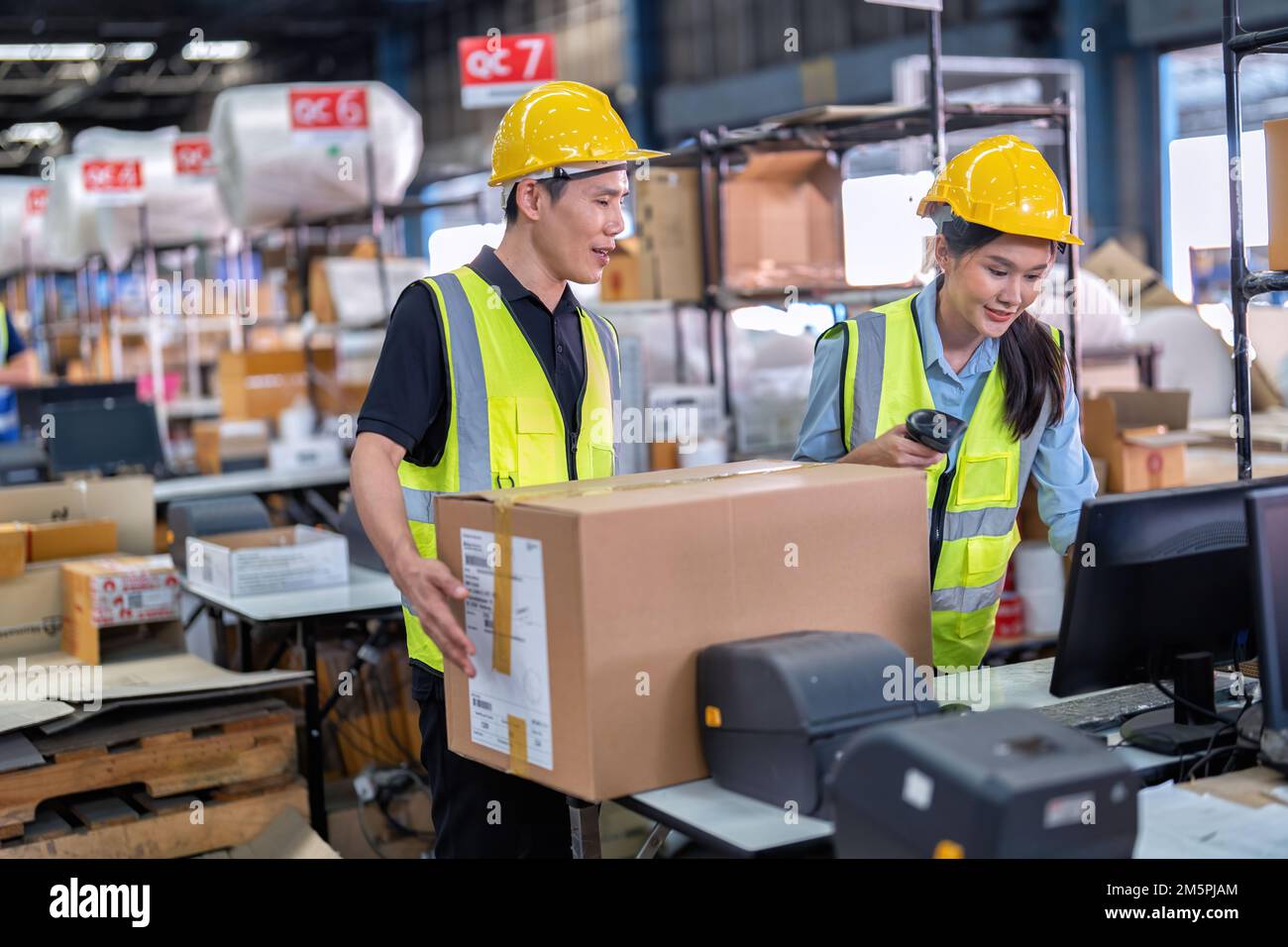 2 Staff working in large depot storage warehouse check packing box and ...