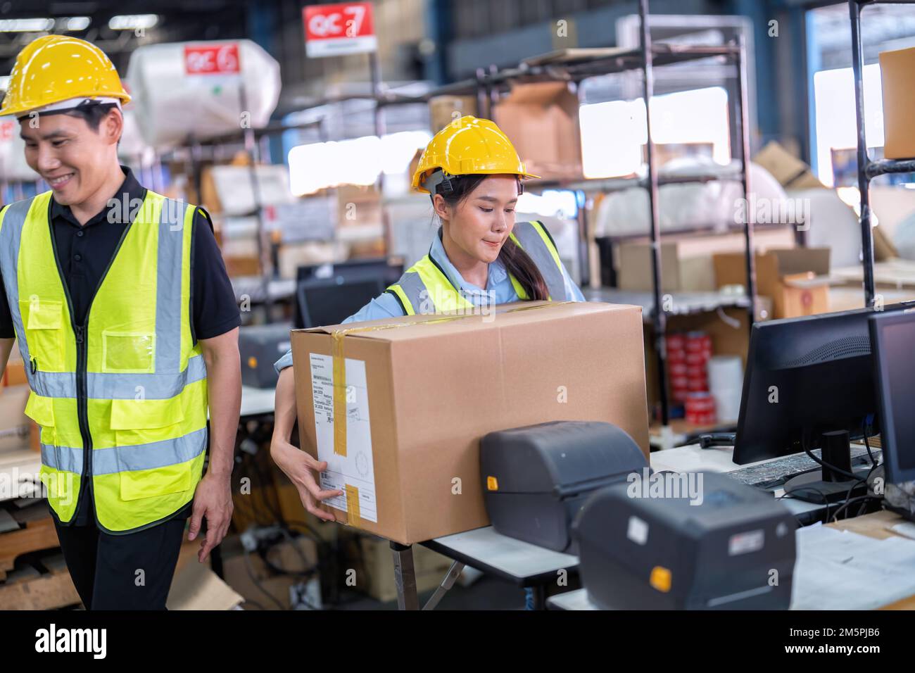 2 Staff working in large depot storage warehouse check packing box and ...