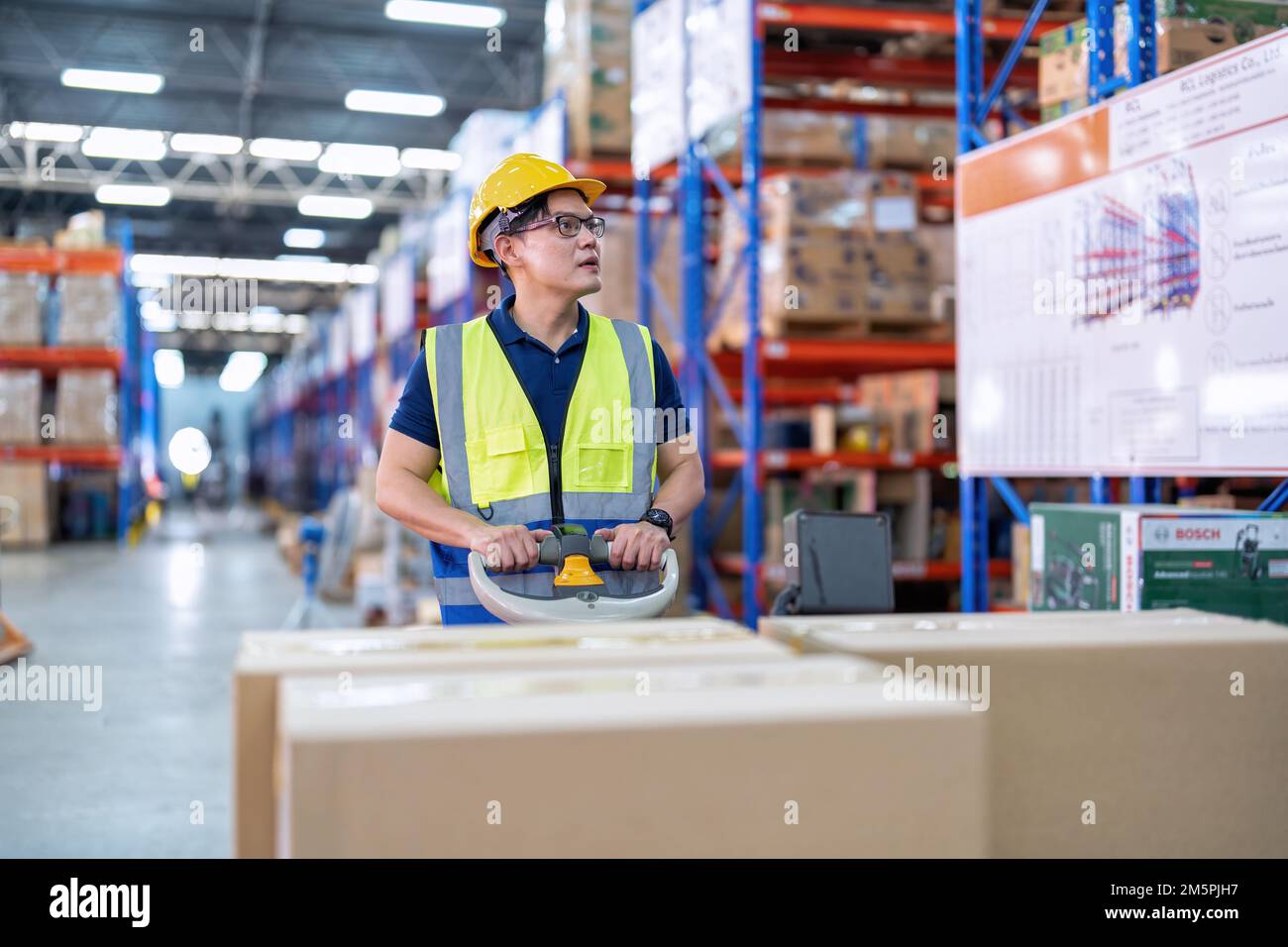 Worker in large depot storage warehouse use machine pallet truck carry ...