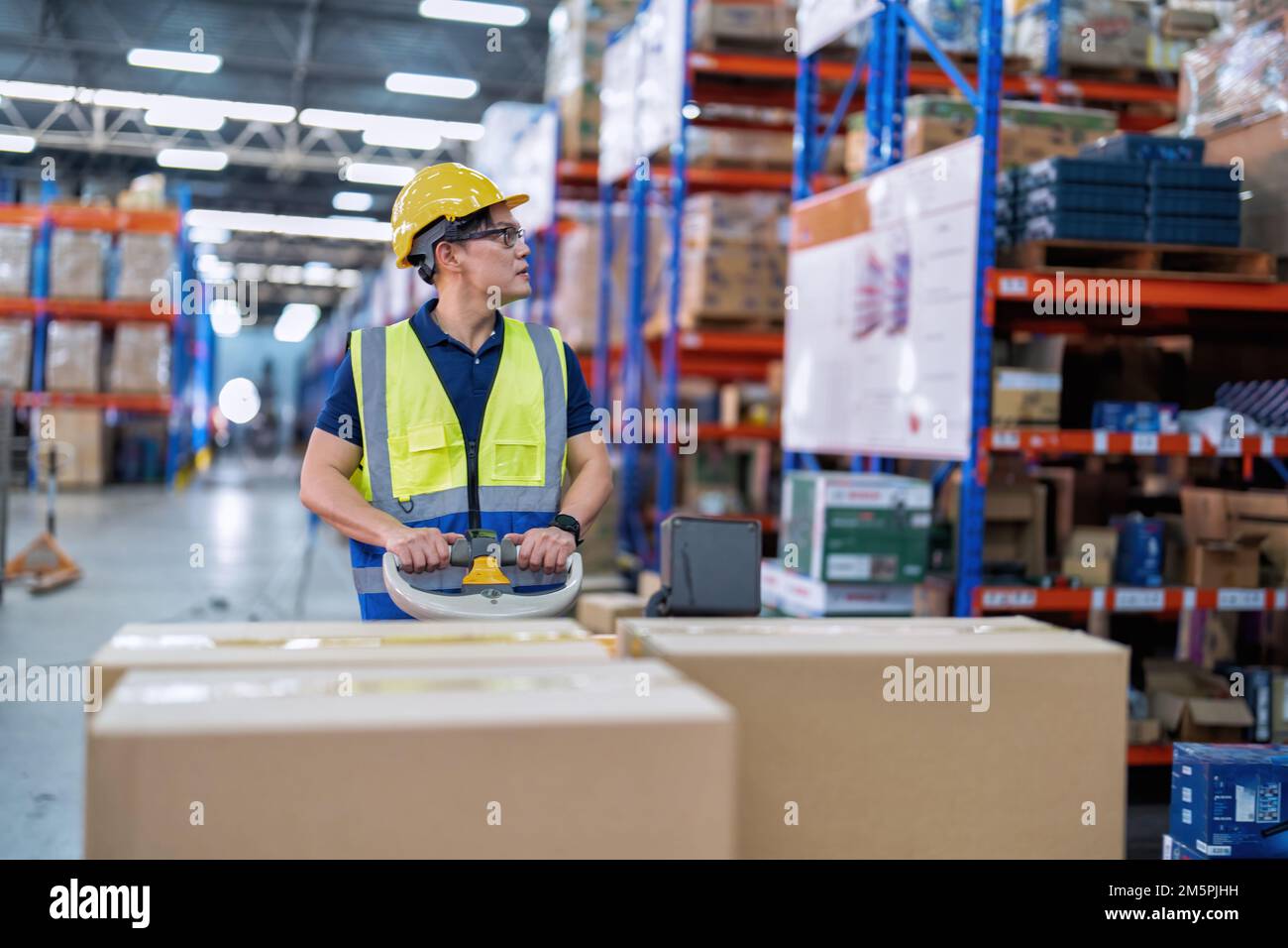 Worker in large depot storage warehouse use machine pallet truck carry ...