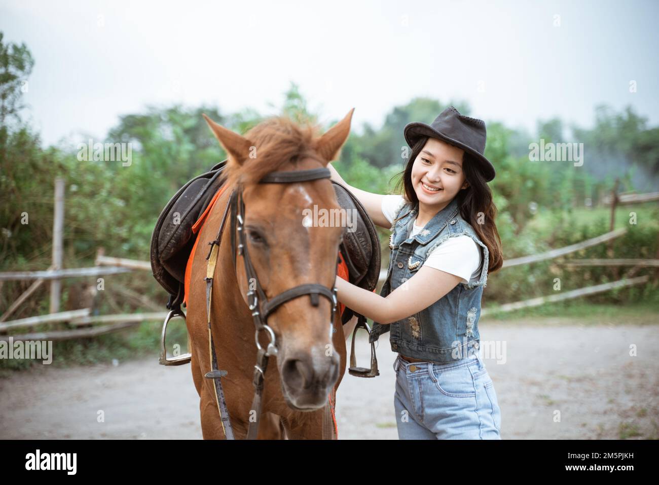beautiful asian cowboy girl standing beside horse on outdoor background ...
