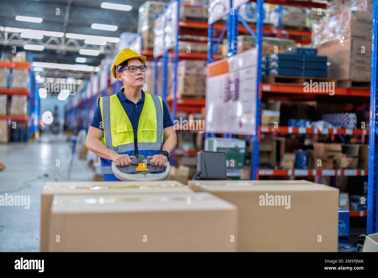 Worker in large depot storage warehouse use machine pallet truck carry ...