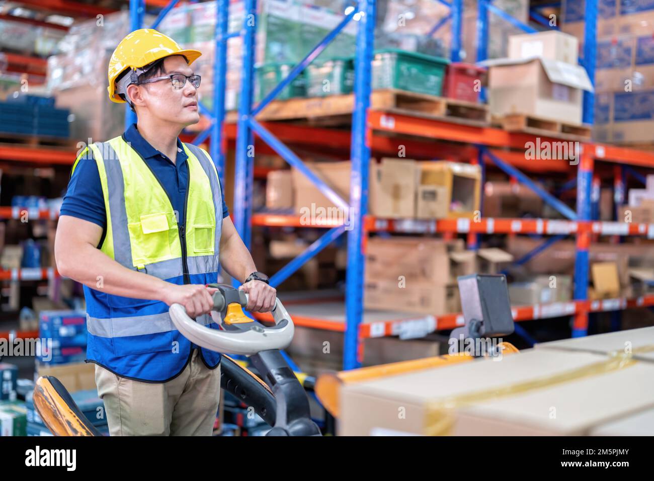 Worker in large depot storage warehouse use machine pallet truck carry ...