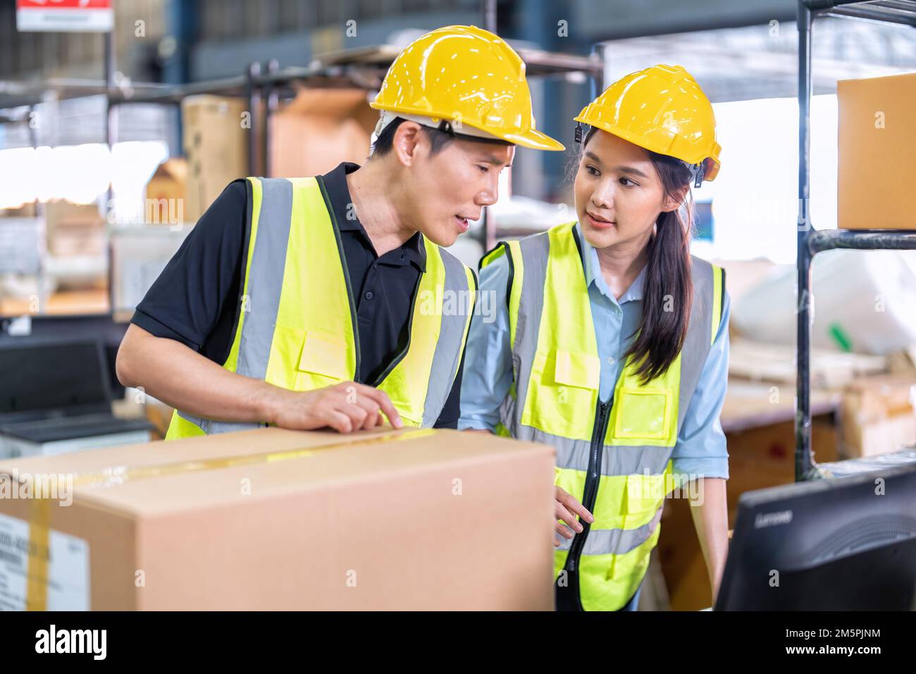 Staff working in large depot storage warehouse trainee check packing box and scan at cashier ...