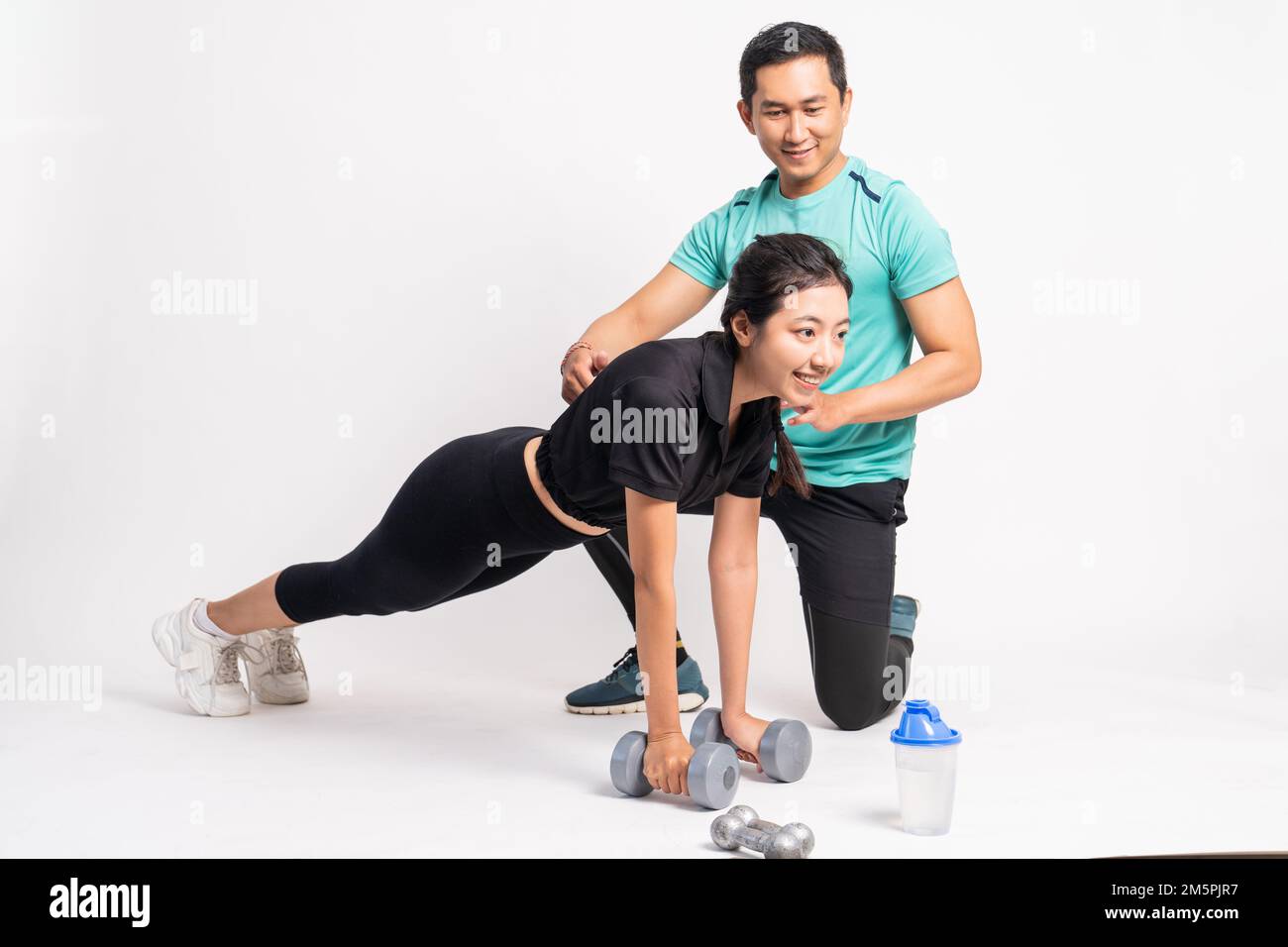 side view of woman pushing up with trainer helping her Stock Photo - Alamy